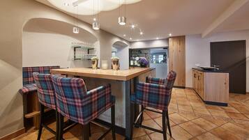 Cozinha moderna com espaço de bar, destacando bancada de madeira, banquetas e iluminação pendente.