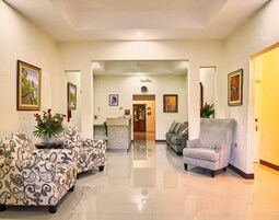 Um hall amplo com sofás estampados, um balcão de recepção e obras de arte emolduradas nas paredes.