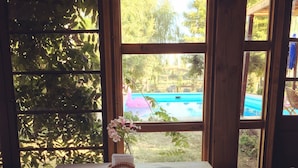Mesa posta para dois com vista para uma piscina através de grandes janelas.