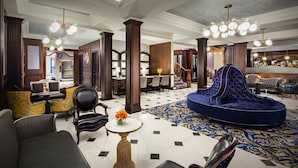Um hall amplo com uma escadaria imponente, assentos elegantes e um espaço de bar.