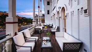 Terraço no telhado com assentos acolchoados brancos, uma mesa com pratos e copos, e vista para a paisagem urbana.