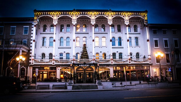 Um hotel histórico com fachada imponente, vários andares e uma entrada central decorada com uma árvore de Natal.