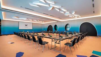 Uma sala de conferência com uma mesa comprida, várias cadeiras e uma tela grande exibindo o logotipo "SUZHOU".