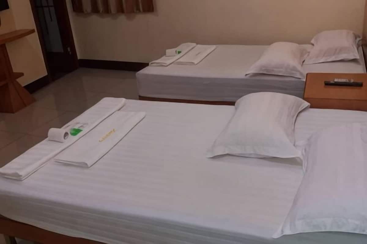 Quarto de hotel com duas camas, cada uma com toalhas brancas e almofadas dobradas.