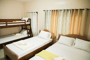 Quarto com duas camas de solteiro e uma beliche, cada uma com roupa de cama e almofadas brancas.