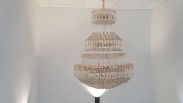 Um lustre de cristal em vários níveis pendurado no teto de um quarto com paredes brancas.