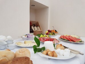 Uma mesa com diversos alimentos, incluindo queijo, frutas e pão.