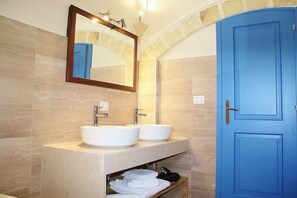 Casa de banho com duas pias, um espelho e uma porta azul.
