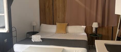 Quarto moderno com uma cama grande, mesas de cabeceira, luminária pendente e vista para o exterior.