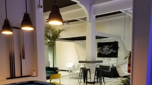 Mesa de bilhar em ambiente com design moderno, incluindo iluminação pendente e área de estar com mesa e cadeiras.