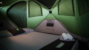 Um quarto com tenda, com uma cama, almofadas, um cobertor e toalhas.