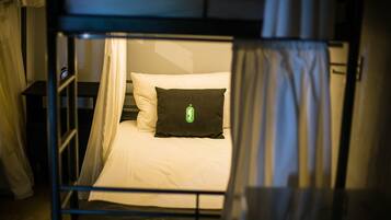 Uma cama beliche com colchão branco e travesseiro preto com logotipo verde.