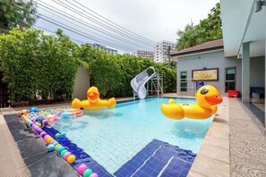Uma piscina com patos infláveis e um escorrega.