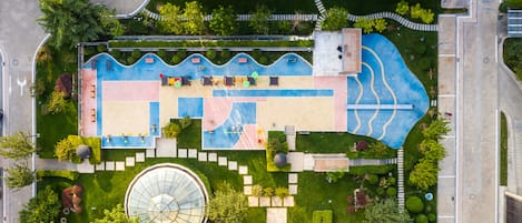 Vista aérea de um edifício moderno com um jardim no terraço, piscina e uma estrutura circular de vidro.