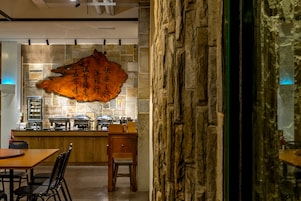 Interior de restaurante com parede de pedra, balcão de madeira e uma peça decorativa grande.