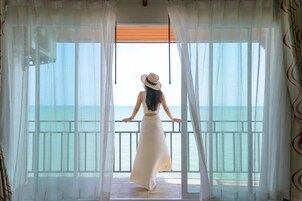 Quarto com vista para o mar através de cortinas finas.