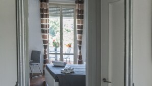 Um quarto com uma cama, uma cadeira e uma janela com cortinas.