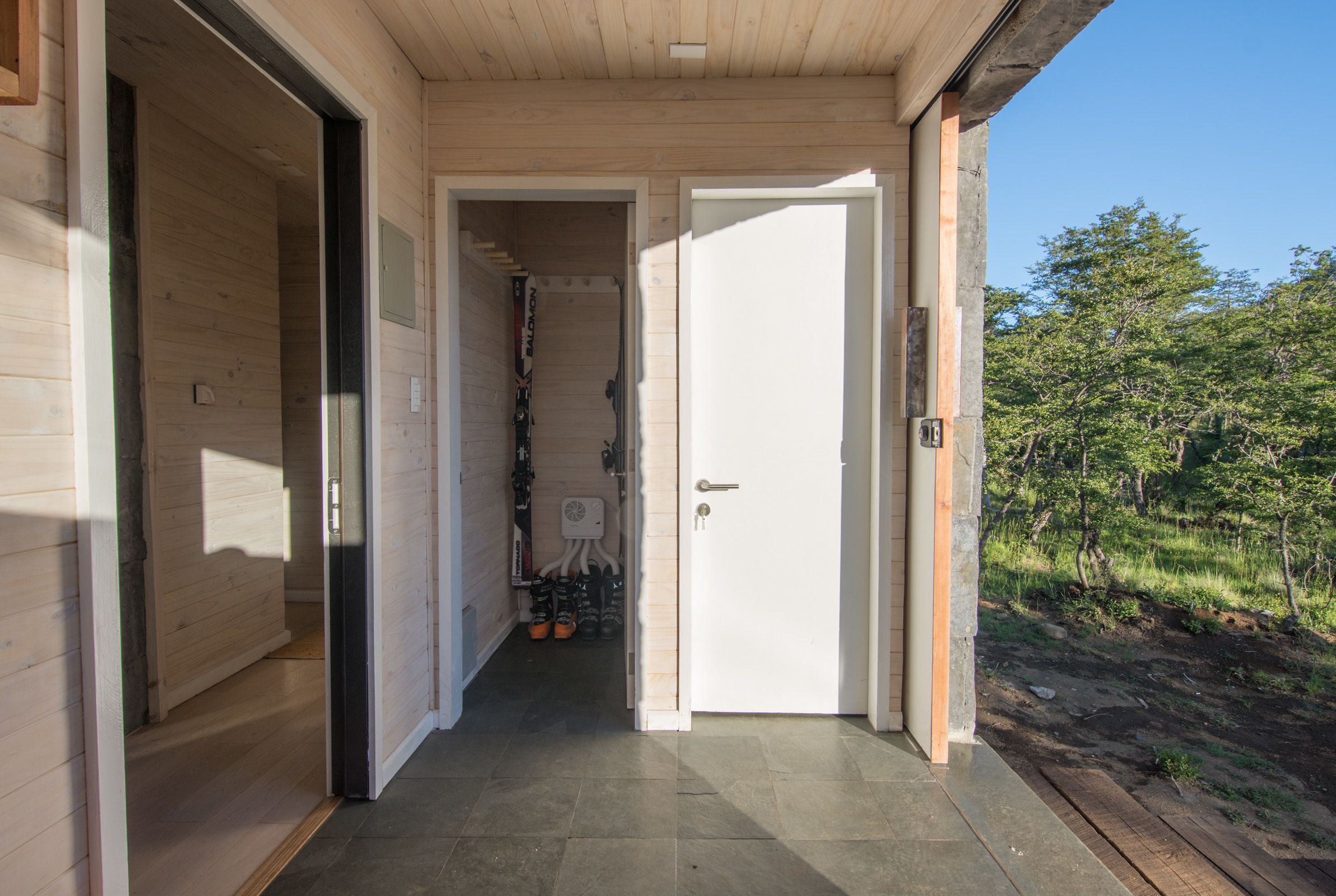Um corredor de madeira com uma porta que dá para um quarto com ventilador e janela.