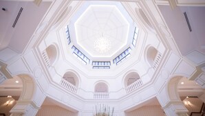 Um salão imponente com um grande claraboia octogonal e um lustre central.