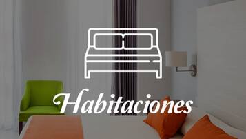 Quarto de hotel com uma cama, uma poltrona verde e uma mesa de cabeceira com luminária.