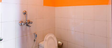 Casa de banho com azulejos brancos, uma parede laranja, sanita branca e chuveiro com torneira cromada.