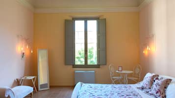 Quarto com cama, cadeira, mesinha e espelho.