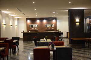 Um saguão de hotel com área de bar, assentos e balcão de recepção.