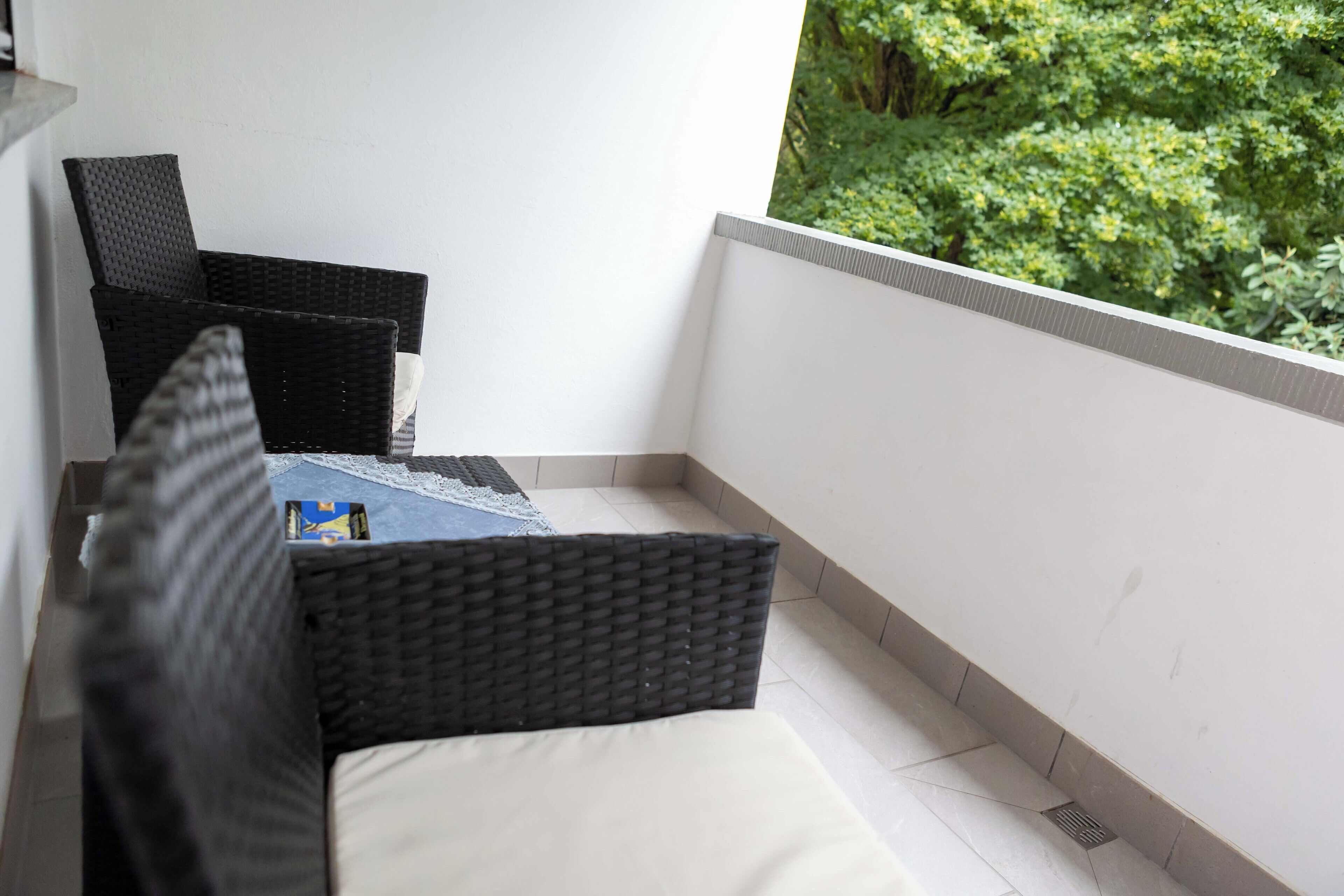 Varanda com mobiliário de vime e vista para o verde.