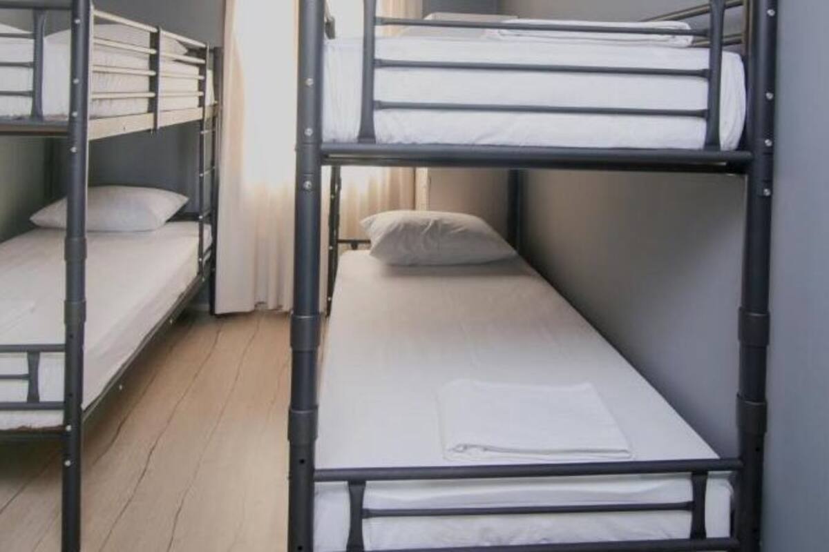 Quarto com beliches, piso de madeira e cortina.