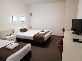Quarto de hotel com duas camas, uma escrivaninha com computador e televisão.