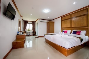 Quarto de hotel com uma cama grande, uma escrivaninha, uma cadeira, uma televisão e vista para o exterior.