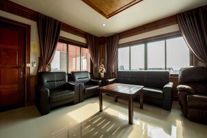 Uma sala de estar moderna com sofás de couro, uma mesa de centro de madeira e grandes janelas com cortinas.