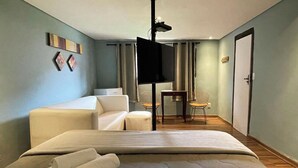 Quarto de hotel com cama, televisão, escrivaninha e cadeira.