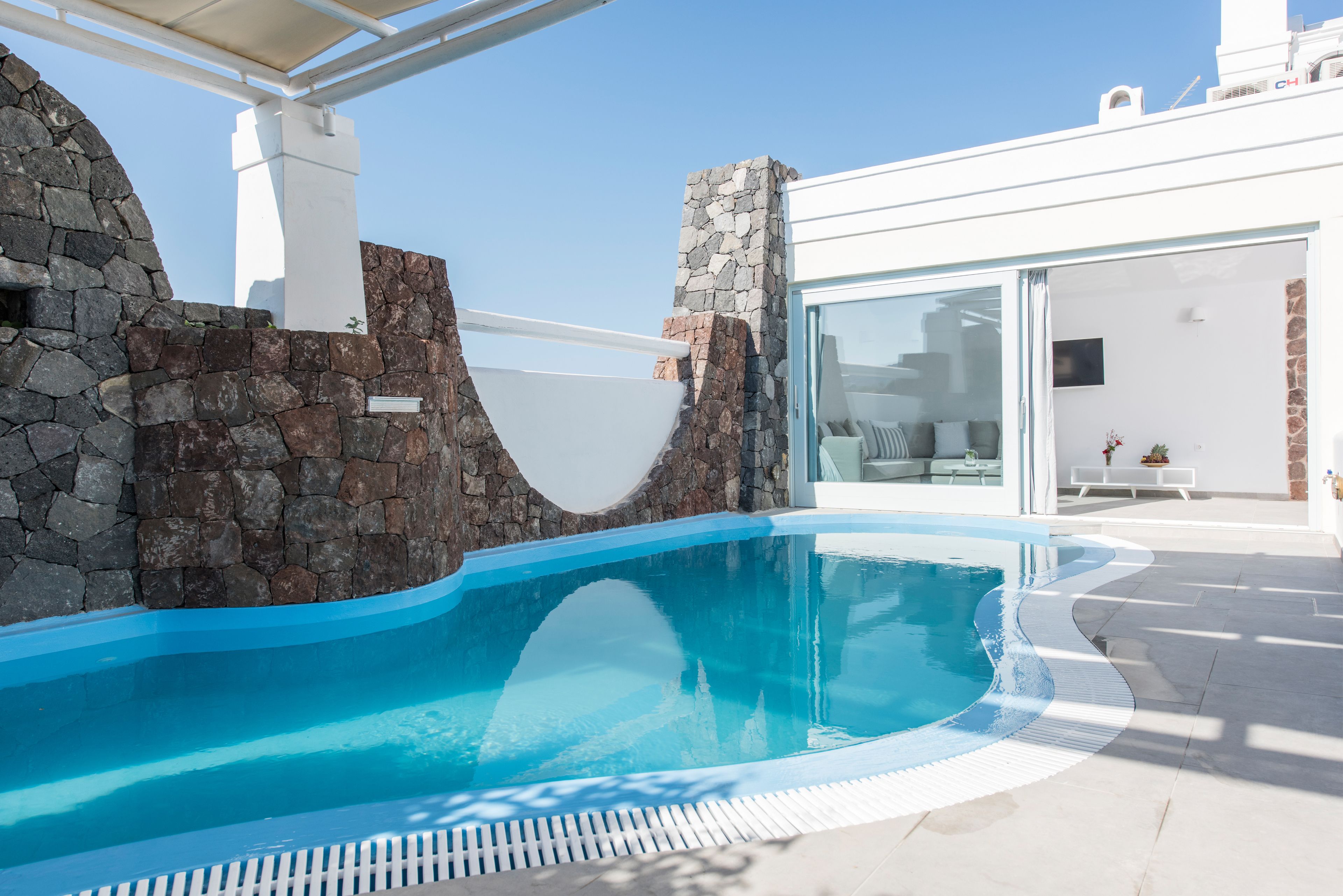Piscina com paredes de pedra e área externa moderna.