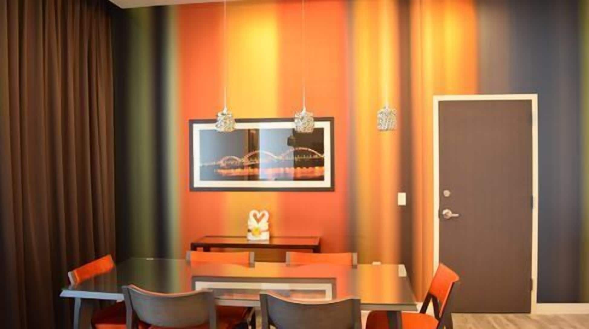 Uma área de refeições moderna com uma mesa, cadeiras, um quadro na parede e uma porta.