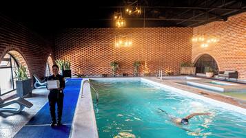 Piscina interior com parede de tijolos, salva-vidas e um nadador.