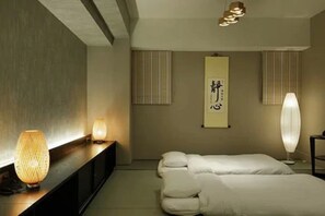 Quarto de hotel minimalista com cama, luminárias de cabeceira, uma obra de arte na parede e mesa de cabeceira.