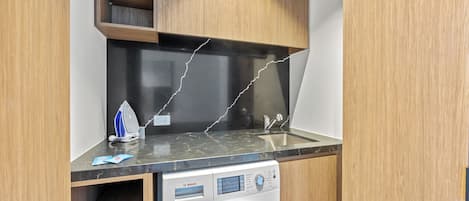 Uma cozinha compacta com máquina de lavar Bosch, bancada preta e armários de madeira.