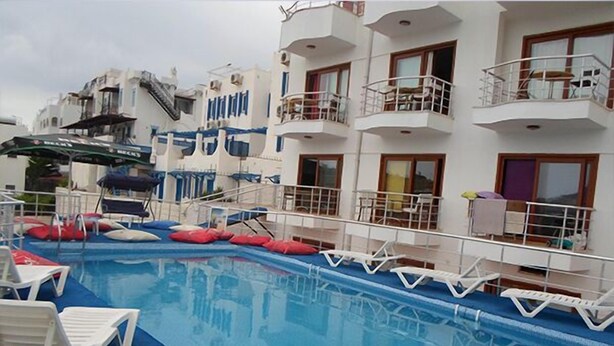 Área de piscina com espreguiçadeiras e trampolim.