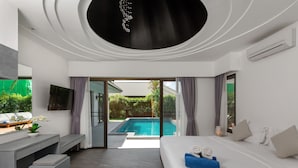 Quarto moderno com uma cama grande, televisão e vista para uma piscina ao ar livre.