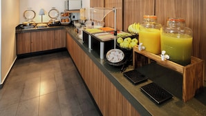 Um buffet de café da manhã com diversas opções de alimentos e bebidas.