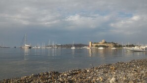 Um porto com barcos, um castelo e uma costa rochosa.