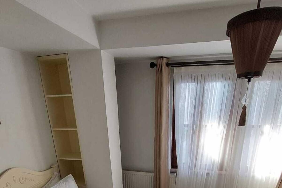 Cama bem arrumada em quarto de hotel, com cabeceira de madeira, mesa de cabeceira e uma cadeira pequena.