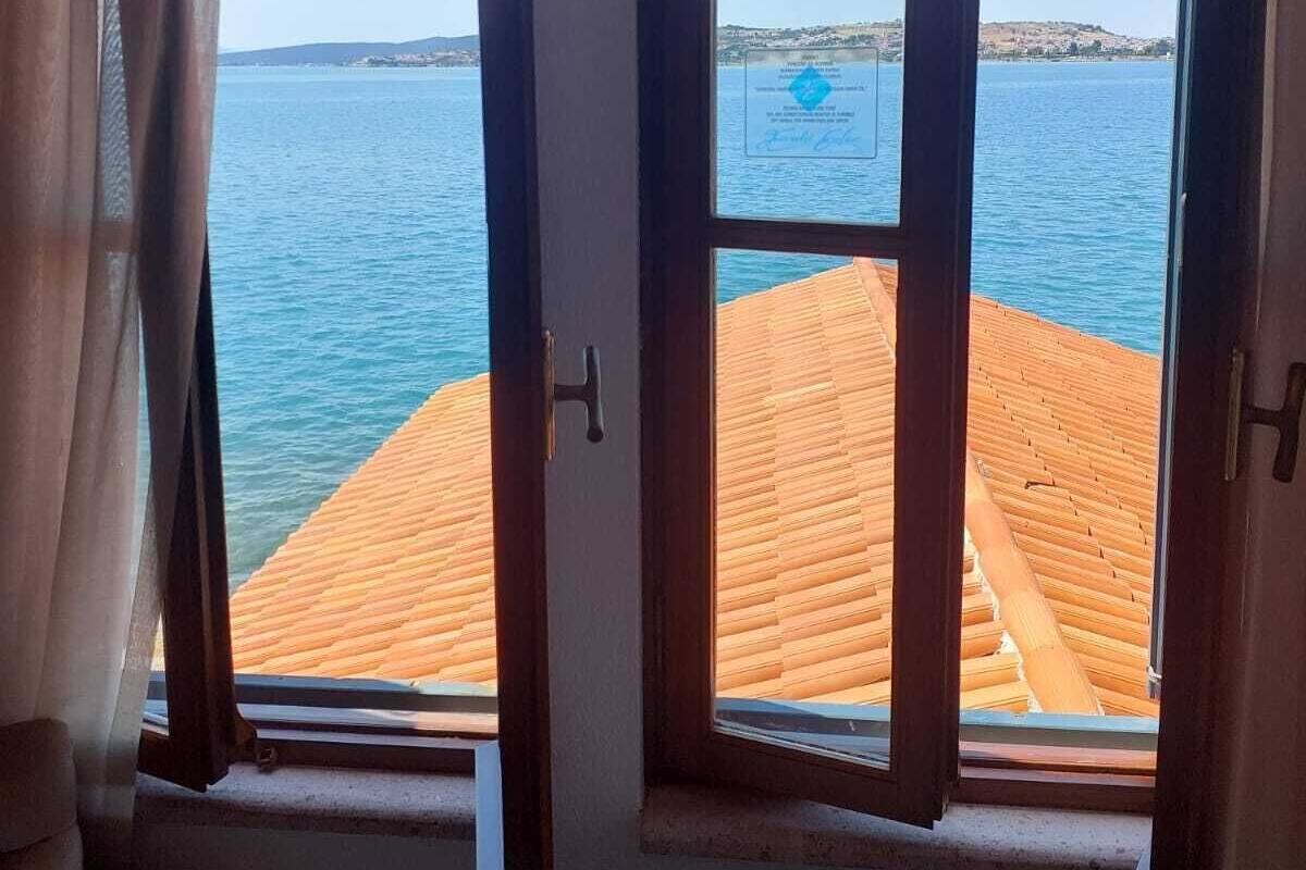 Quarto com uma grande janela com vista para um deck de madeira e um corpo d'água.