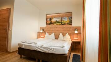 Quarto com cabeceira de madeira, cama com roupa de cama branca, duas luminárias de cabeceira e um quadro sobre a cama.