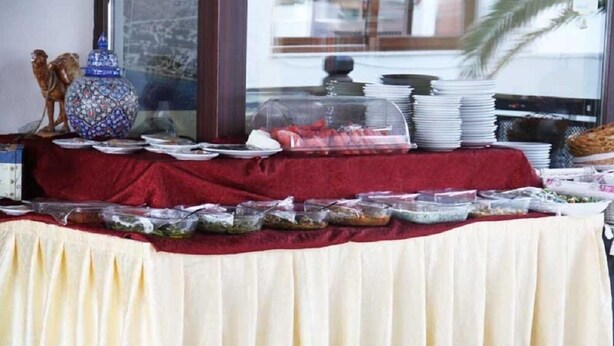 Uma mesa de buffet com diversos alimentos e um vaso decorativo.