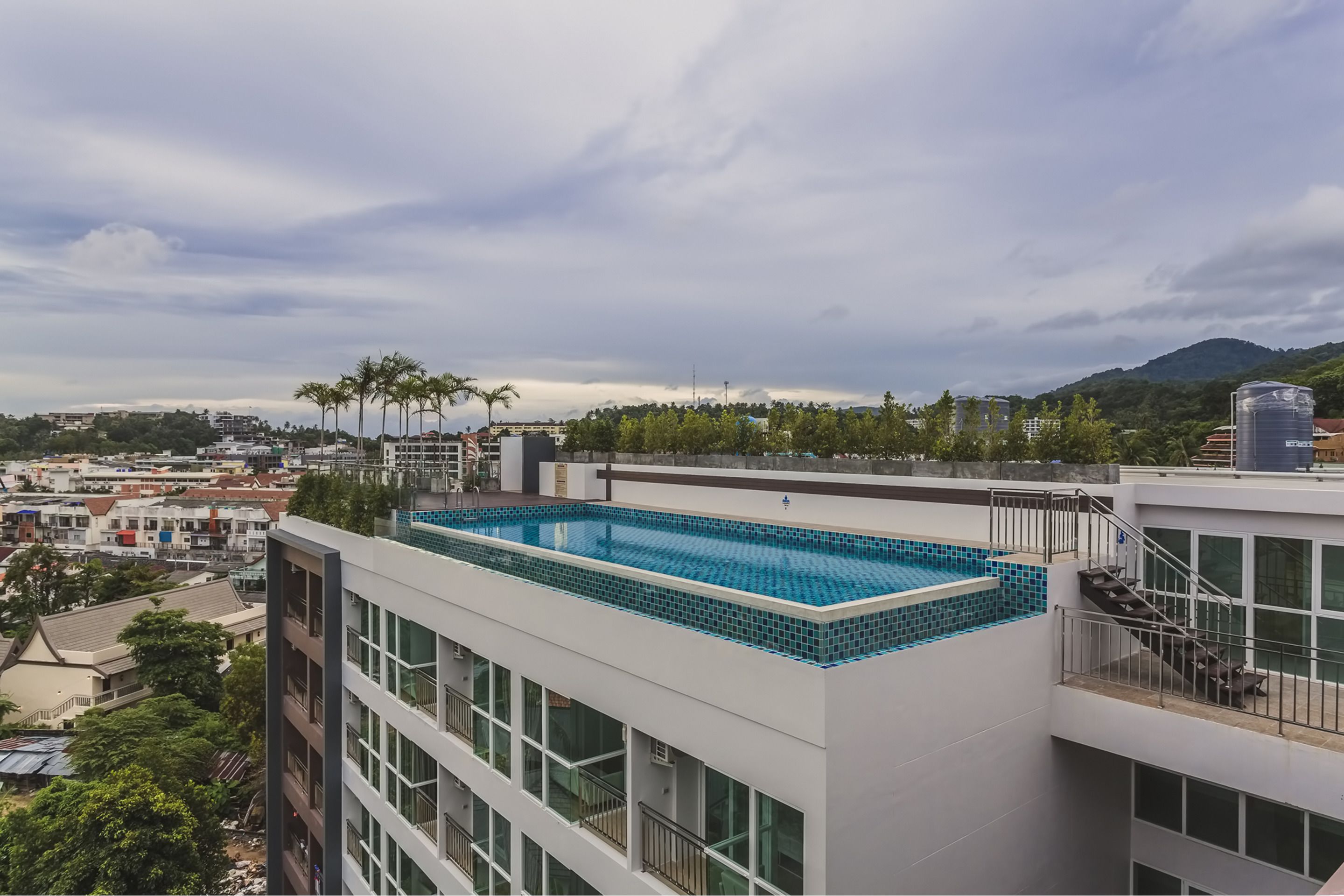 Piscina no terraço com vista para edifícios próximos e uma montanha ao fundo.