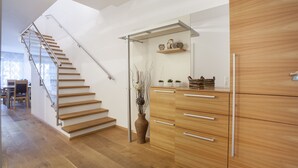 Um interior moderno com escada de madeira, armário de madeira e um vaso com galhos.
