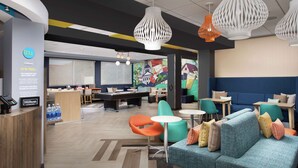 Um hall de hotel moderno com mesa de bilhar, assentos confortáveis e um mural vibrante.