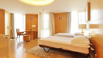 Quarto de hotel com cama, escrivaninha, cadeira e luminária.